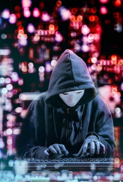 Premium Photo Computer Hacker Wearing Mask And Hooded Shirt While Tying On Keyboard Against