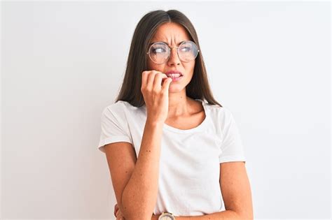 캐주얼 티셔츠와 안경을 입고 고립 된 흰색 배경 위에 젊은 아름다운 여성은 손톱을 물고 입에 손을 긴장 찾고 불안 문제 T 셔츠에 대한 스톡 사진 및 기타 이미지 Istock