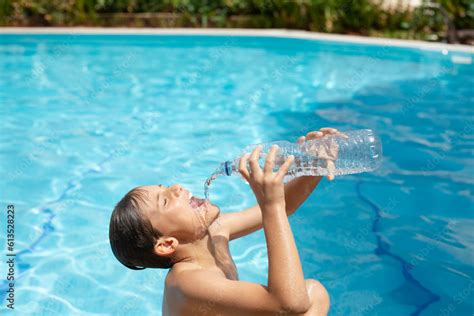 Young Man Hydrating With Water In The Pool Due To A Heat Wave In Summer