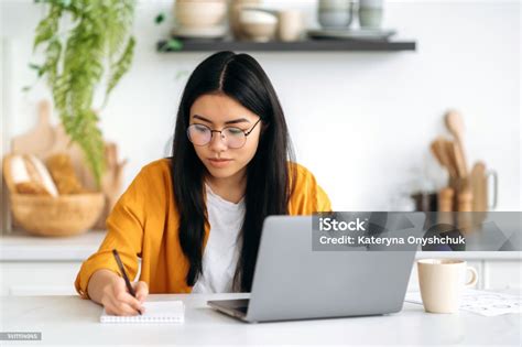 온라인 교육 전자 학습 개념 안경을 쓴 영리한 긍정적 인 아시아 소녀 성공적인 학생 랩톱을 사용하여 집에서 공부 온라인 웨비나 듣기 수업 메모 작성 친절한 미소 짓기 검사