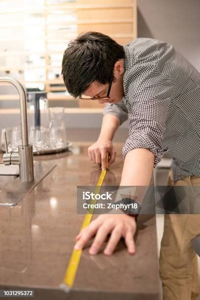 젊은 아시아 남자 쇼 룸에서 현대 부엌 카운터에 화강암 싱크대를 측정 하기 위한 측정 테이프를 사용 하 여 홈 개선 위한 가구 쇼핑 인테리어 디자인 컨셉 가구에 대한 스톡