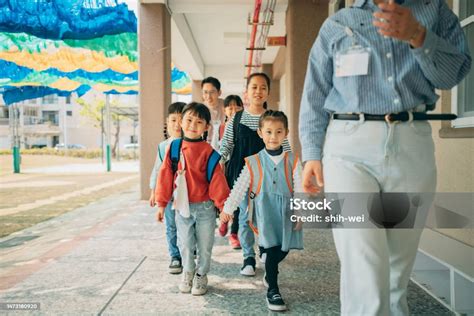 두 명의 아시아 유치원 교사가 아이들에게 질서 정연하게 줄을 서서 교실에 들어갈 준비를하도록 안내하고 있습니다 걷기에 대한 스톡 사진 및 기타 이미지 Istock
