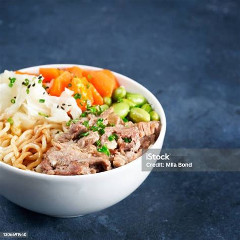 포크 그릇 돼지 고기 야채 Pumkin 콩 에다마메 국수 그릇 젓가락 복사 공간 클로즈업 하와이 요리 파란색 어두운 배경 트렌디 한 아시아 음식 건강하고 깨끗한 식사 개념