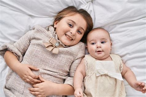 Brother And Sister Smiling Confident Lying Together On Bed At Bedroom