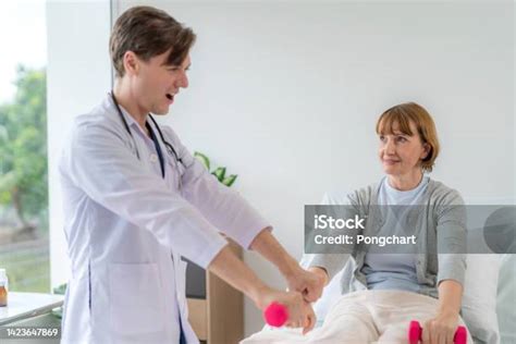 백인 노인 환자 여성은 침대에 앉아서 병원에서 치료 후 운동하기 위해 덤벨을 들어 올립니다 의사와 함께 운동 의료 의료 및 물리 치료사 보험 개념 2명에 대한 스톡 사진 및