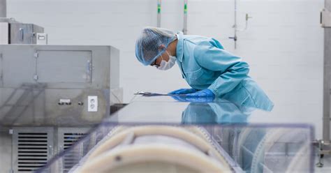 파란색 실험실 정장을 입은 백인 공장 노동자 손에 태블릿 제조 기계에 구부리기 사진 Unsplash의 능률 이미지