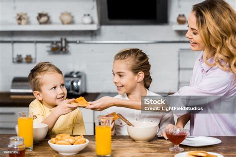 부엌에서 어머니 로부터 잼 토스트를 복용 하는 동생을 보고 웃는 소녀 가족에 대한 스톡 사진 및 기타 이미지 가족 부엌