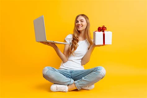 노란색 배경에 노트북 및 그녀의 손에 선물 상자와 바닥에 앉아 흥분 여자의 초상화 쇼핑에 대한 스톡 사진 및 기타 이미지 쇼핑 승리 동작 활동 크리스마스 Istock