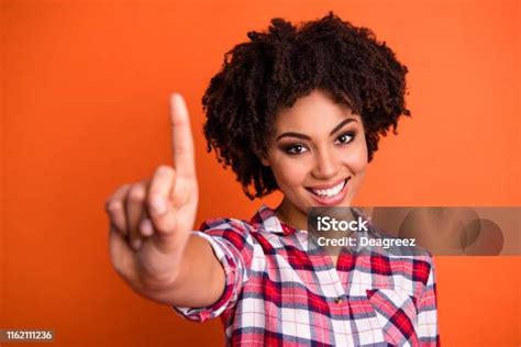 그녀의 클로즈업 초상화 그녀의 좋은 매력적인 쾌활한 쾌활한 콘텐츠 물결 모양의 머리 여자 를 입고 체크 셔츠를 주는 1 단일 기호 밝은 선명한 빛나는 오렌지 배경 위에 고립