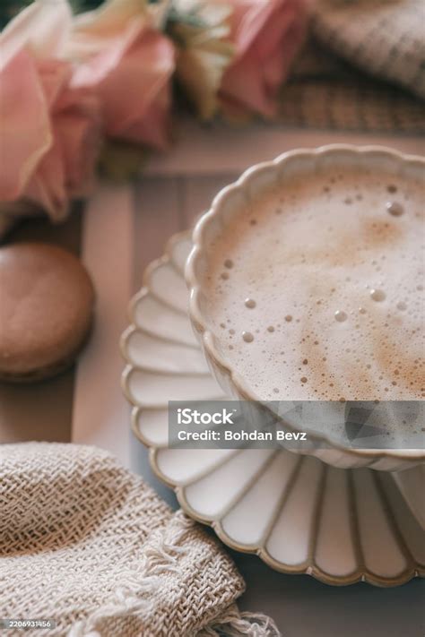 무채색 패브릭 배경에 거품 커피 한 잔 분홍색 마카롱 부드러운 분홍색 장미를 놓고 평평하게 누워 있습니다 파스텔과 베이지 톤의 우아하고 아늑한 구성 감정에 대한 스톡 사진