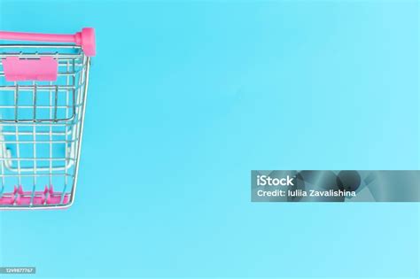 작은 슈퍼마켓 식료품 푸시 카트 는 파란색 파스텔 화려한 트렌디 한 배경 복사 공간에 고립 된 바퀴와 장난감을 쇼핑 쇼핑몰 시장 점 소비자 개념 판매 구매 가방에 대한 스톡