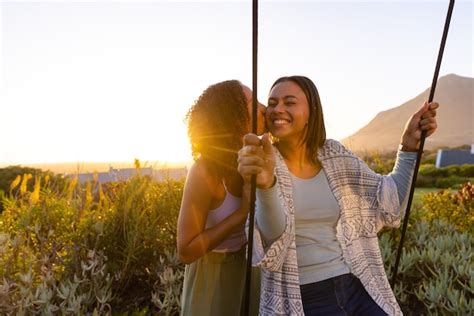 Premium Photo Happy Biracial Lesbian Couple Kissing And Swinging On
