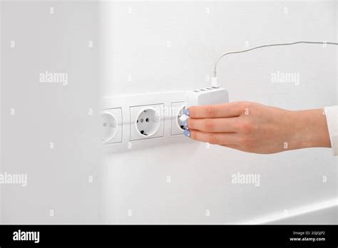 Woman Putting Plug Into Socket In Room Stock Photo Alamy