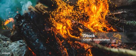 불에 타버린 생생한 연기가 나는 장작이 클로즈업되었습니다 모닥불과 푸른 연기의 주황색 불꽃이 있는 분위기 있는 배경 모닥불의 따뜻한 풀 프레임 이미지 공중에서 빛나는 불씨