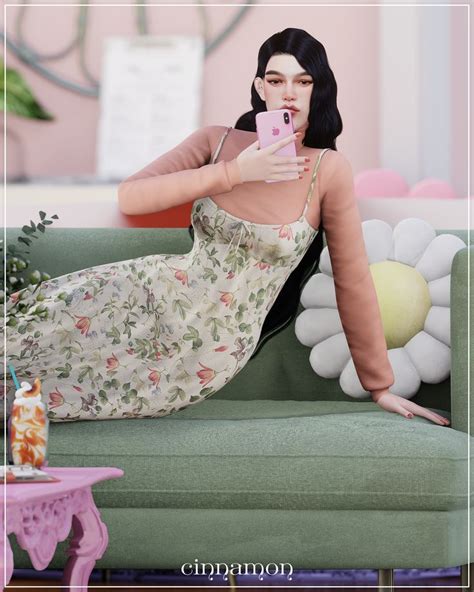 A Woman Sitting On Top Of A Green Couch Holding A Cell Phone In Her Hand