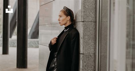 검은 코트와 검은 바지를 입은 여자 회색 콘크리트 벽에 기대어 사진 Unsplash의 무료 초상 이미지