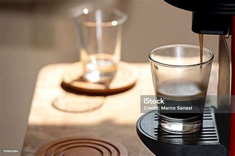 두 개의 샷 안경과 전경에 샷 유리에 커피를 붓는 커피 머신의 일부와 부엌에서 나무 테이블 우정에 대한 스톡 사진 및 기타 이미지 우정 커피 마실 것 근거리 초점