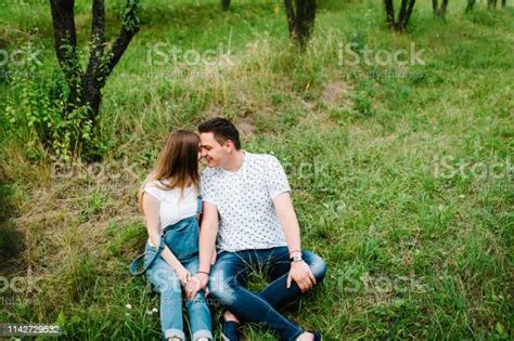 임신 한 여자와 그녀의 남편은 포옹 행복 뱃속에 손을 잡고 정원 배경에서 야외에서 잔디에 앉아 닫습니다 전체 길이 서로 봐 2명에 대한 스톡 사진 및 기타 이미지 Istock
