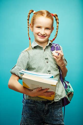 그녀의 어깨와 손에 노트북에 배낭과 젊은 웃는 학생은 고립 된 파란색 배경에 서 있으며 좋은 분위기를가지고 있으며 학교 유니폼을 착용 합니다 여 학생가 학교에가 고등학교