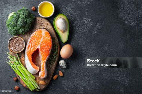 어두운 배경에 Keto 다이어트에 대 한 건강 식품의 집합입니다 아마 씨앗 브로콜리 아보카도 계란 견과류와 나무 보드에 아스파라거스와 신선한 생 연어 스테이크 복사 공간