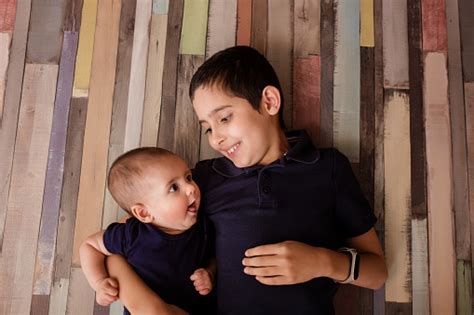 갈색 배경에 그의 팔에 신생아 소년을 들고 행복한 형제 형제 가족 친구 신생아 포토세션 2명에 대한 스톡 사진 및 기타 이미지 Istock