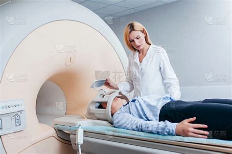 放射模型技术员帮助成熟的女性病人躺在ct扫描床上，看着相机素材 花瓣网