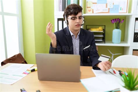 non binary man call center agent using computer and credit card working