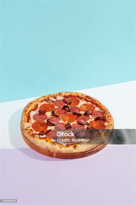 소시지 살라미 페퍼로니를 색칠한 배경에 곁들인 이탈리아 피자 살라미와 페퍼로니를 곁들인 고기 피자는 파란색으로 최소한의 스타일로 제공됩니다 색상 배경을 가진 미국 피자 배달