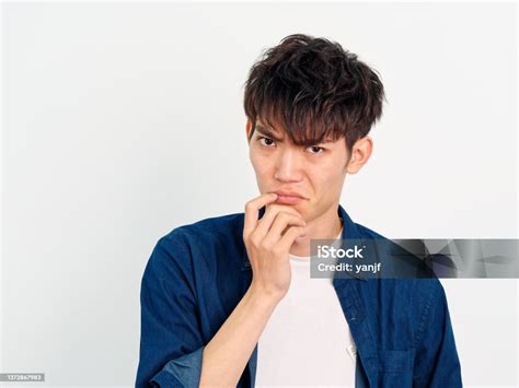 흰색 벽 배경에 포즈 파란색 셔츠에 곱슬 검은 머리를 가진 잘 생긴 중국 젊은이의 초상화 혐오스무분이 있는 표정으로 입에 손을