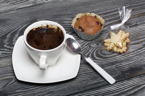 흰 컵에 커피가 접시 위에 서 있습니다 근처에는 머핀과 접시에 숟가락이 놓여 있습니다 가방에 눈송이의 형태로 쿠키 세트 기모 소나무 보드에 검은색에 대한 스톡 사진 및 기타