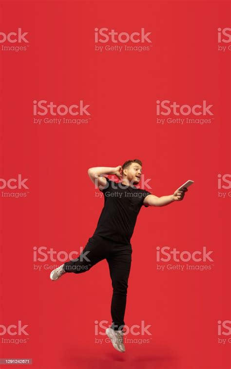 빨간 스튜디오 배경에 고립 된 몸짓을 하는 젊은 성공적인 하이 점프 남자의 전체 길이 초상화 20 24세에 대한 스톡 사진 및