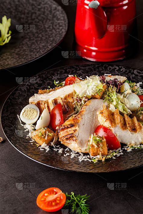 美国的意大利美食凯撒沙拉配上大块烤鸡鹌鹑蛋生菜西红柿帕玛森芝士在餐厅里用黑色的盘子上菜