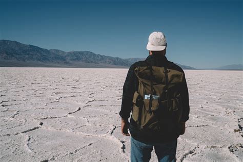 죽음의 계곡에 서있는 배낭을 가진 남자의 백뷰는 미국에서 활동적인 휴가에 야생 의 땅을 탐험 바드 워터 분지의 건조한 황량한 땅에서 숨막히는 풍경을 보고 힙스터 Giu