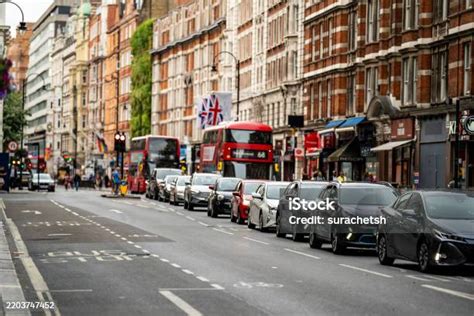 교통 체증에 갇힌 자동차의 긴 줄이있는 바쁜 거리 장면 상징적인 빨간색 2층 버스와 유서 깊은 건물은 도시의 고전적인 분위기를 반영합니다 0명에 대한 스톡 사진 및 기타