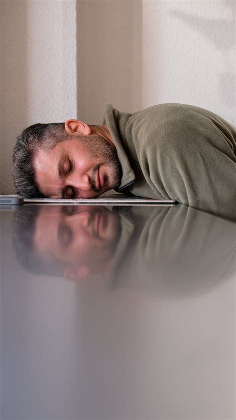 사무실 책상에서 노트북에 머리를 기대고 있는 지친 남자 · 무료 스톡 사진