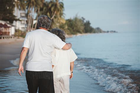 여름 해변 일몰을 산책하는 동안 낭만적 인 아시아 수석 커플이 손을 잡고 있습니다 휴가 와 여름 개념에 은퇴 후 여행 레저 및 활동 2명에 대한 스톡 사진 및 기타 이미지