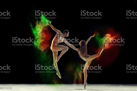 아름다운 젊은 남자와 여자 베이지색 바디수트를 입은 재능 있는 발레 댄서들이 검은 스튜디오 배경에 화려한 가루 폭발과 함께 춤을 춥니다 20 24세에 대한 스톡 사진 및