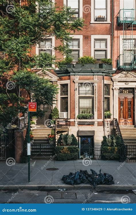 Facade Of A Typical New York House With A Stoop Rubbish In Black Bins