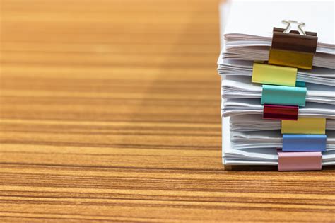 Close Up Pile Of Unfinished Paperwork On Office Desk Waiting To Be
