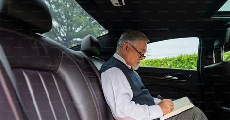 자신감 있는 수석 사업가 Ceo는 안경을 쓰고 자동차 뒷좌석에 앉아 사무실로 출근하는 동안 책에 사업 계획을 씁니다 노인 사업가와 교통 개념 사진 Unsplash의