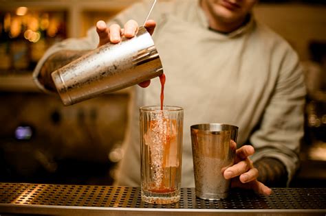 남자 바텐더는 강철 셰이커 잔을 들고 조심스럽게 다른 유리에 빨간 칵테일을 붓습니다 각얼음에 대한 스톡 사진 및 기타 이미지 각얼음 강철 고풍스런 Istock