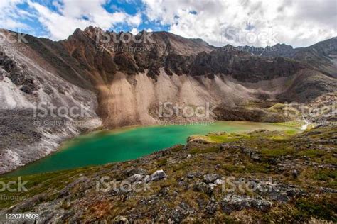구름을 통해 태양에 의해 백라이트 녹색 물과 길쭉한 산 호수 근처의 흰색과 갈색 산 전경에 바위 땅 돌 발톱 수평 경관에 대한 스톡 사진 및 기타 이미지 Istock