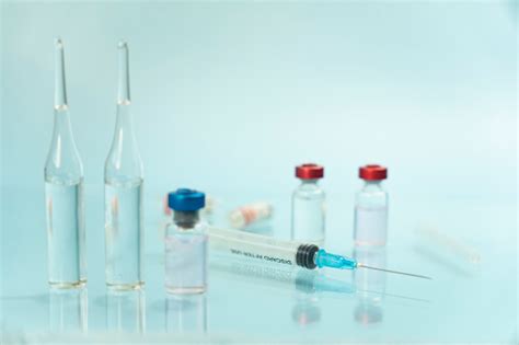 파란색 반사 표면에 바늘이 달린 주사기 옆에 액체가 들어있는 유리 앰플 바이러스 질병 예방 접종 코로나 바이러스 감염으로부터 보호하기위한 예방 접종 0명에 대한 스톡 사진