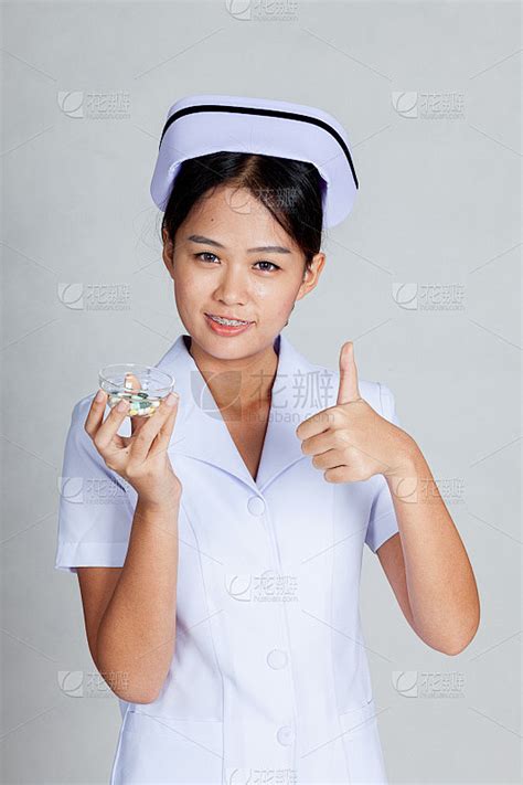 年轻的亚洲护士拿着药片竖起大拇指