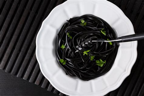 밀 싹 및 검은 오징어 잉크와 함께 파스타입니다 블랙 파스타 그리고 백색 접시에 파 슬 리입니다 매크로입니다 최고의 볼 수 있습니다 0명에 대한 스톡 사진 및 기타 이미지