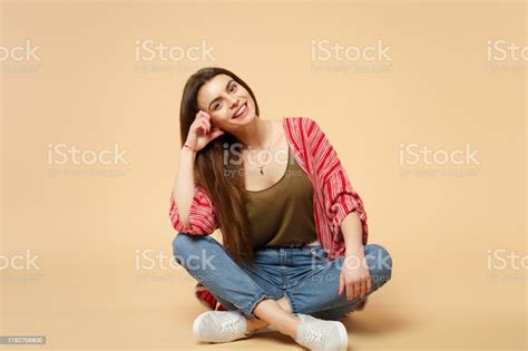 캐주얼 앉아에 쾌활 한 예쁜 젊은 여자의 초상화 스튜디오에서 파스텔 베이 지 벽 배경에 고립 된 카메라를 찾고 사람들은 진심으로