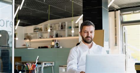 그의 사무실에서 일하는 잘 생긴 젊은 사업가 책상 노트북 태블릿에 앉아 있습니다 사진 Unsplash의 랩톱 이미지