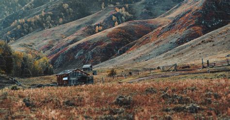 버려진 나무 오두막과 전경의 초원과 언덕 능선 배경에 목초지와 포장 마차 건물이있는 놀라운 산의 풍경 알타이 산맥의 초가을 사진 Unsplash의 평야 이미지