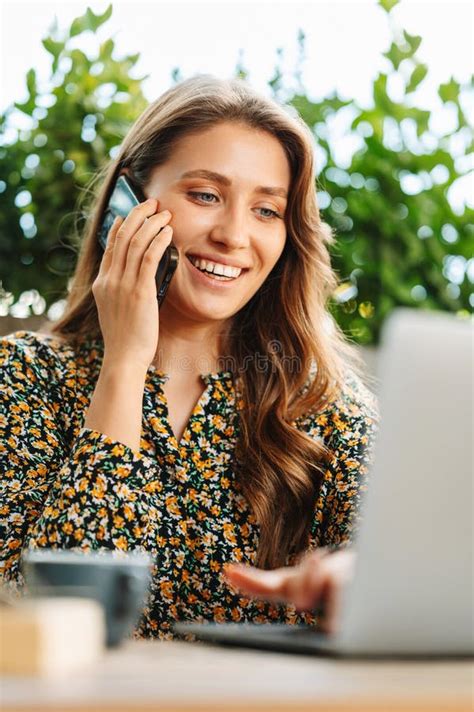 Close Up Shot Of A Smiling Woman Talking On The Phone While Working On