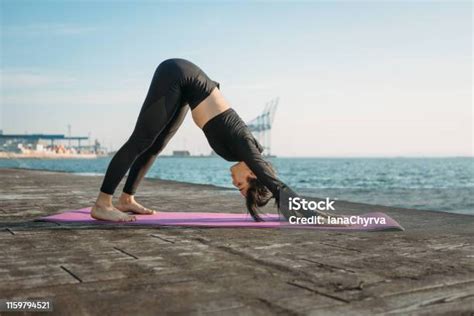 일출에 해변에서 요가를 연습 하는 검은 점프 수트에 젊은 갈색 머리 여자 웰빙과 건강한 라이프 스타일의 개념 가냘픈에 대한 스톡